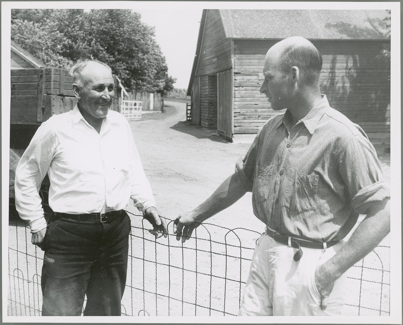 Two men talking by a low wire fence | Iowa State University Photographs